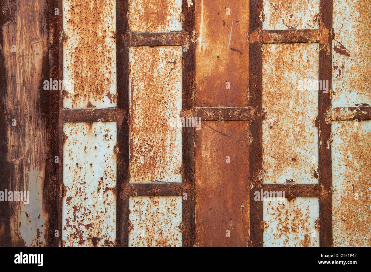 Yellow, brown and red rusted sections of a metal door panel form an ...