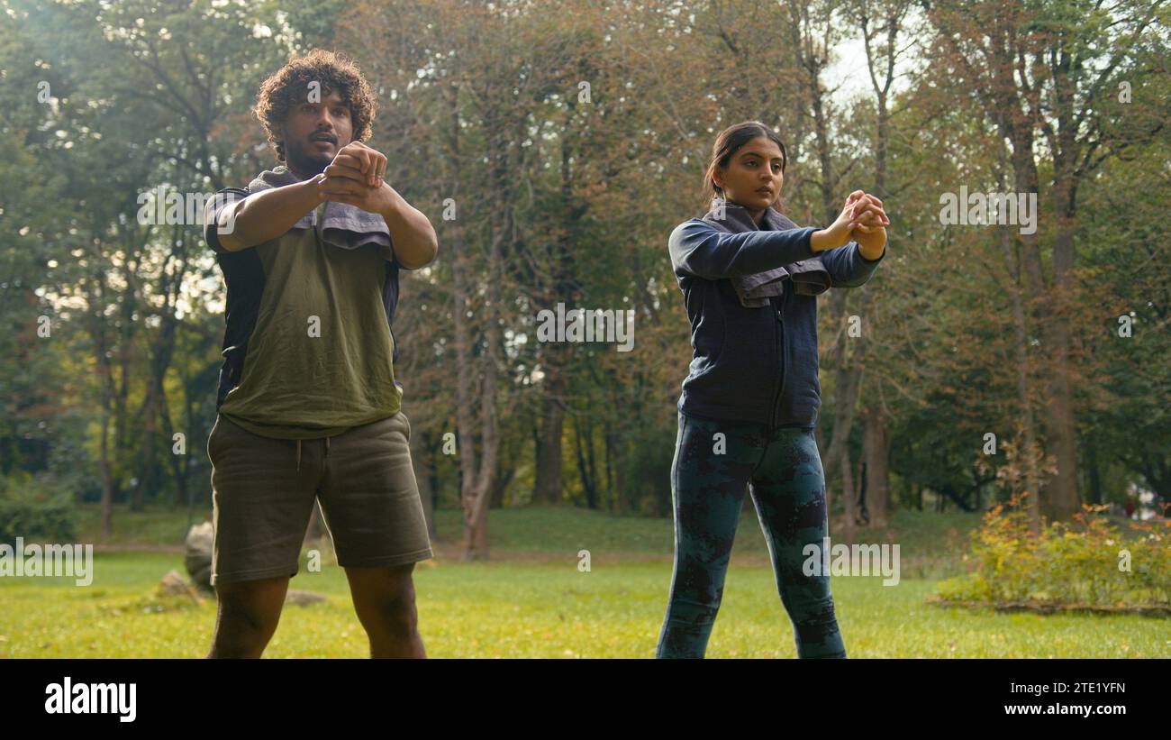 Active sporty two couple doing squats workout exercise in park nature ...
