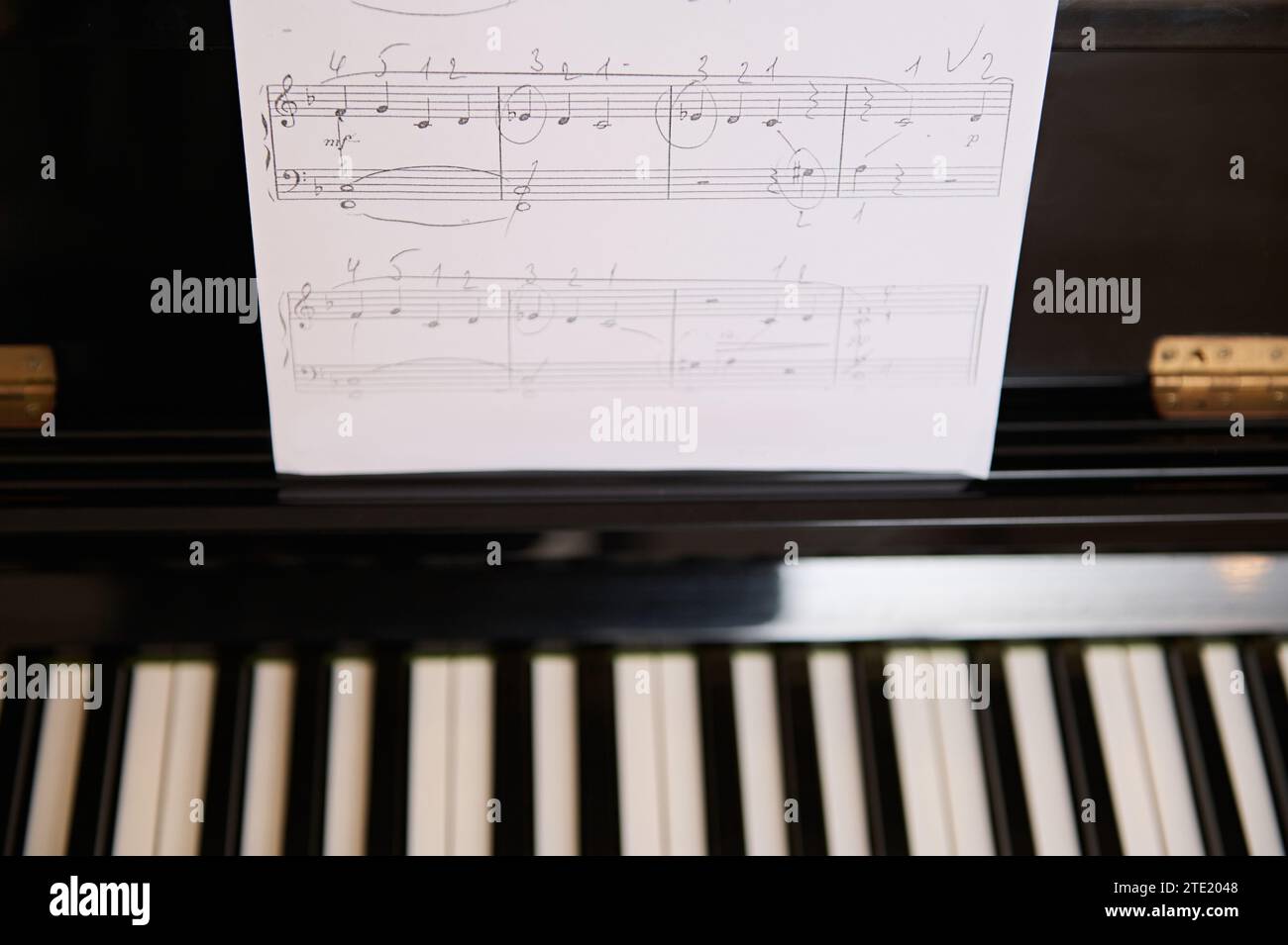 Close-up of white paper sheet with musical notes on old piano. Still ...