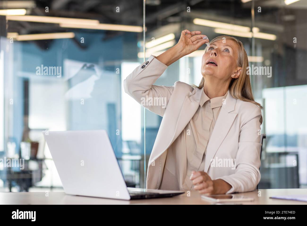 Scared business woman uses eye drops, gray-haired woman overtired sore ...