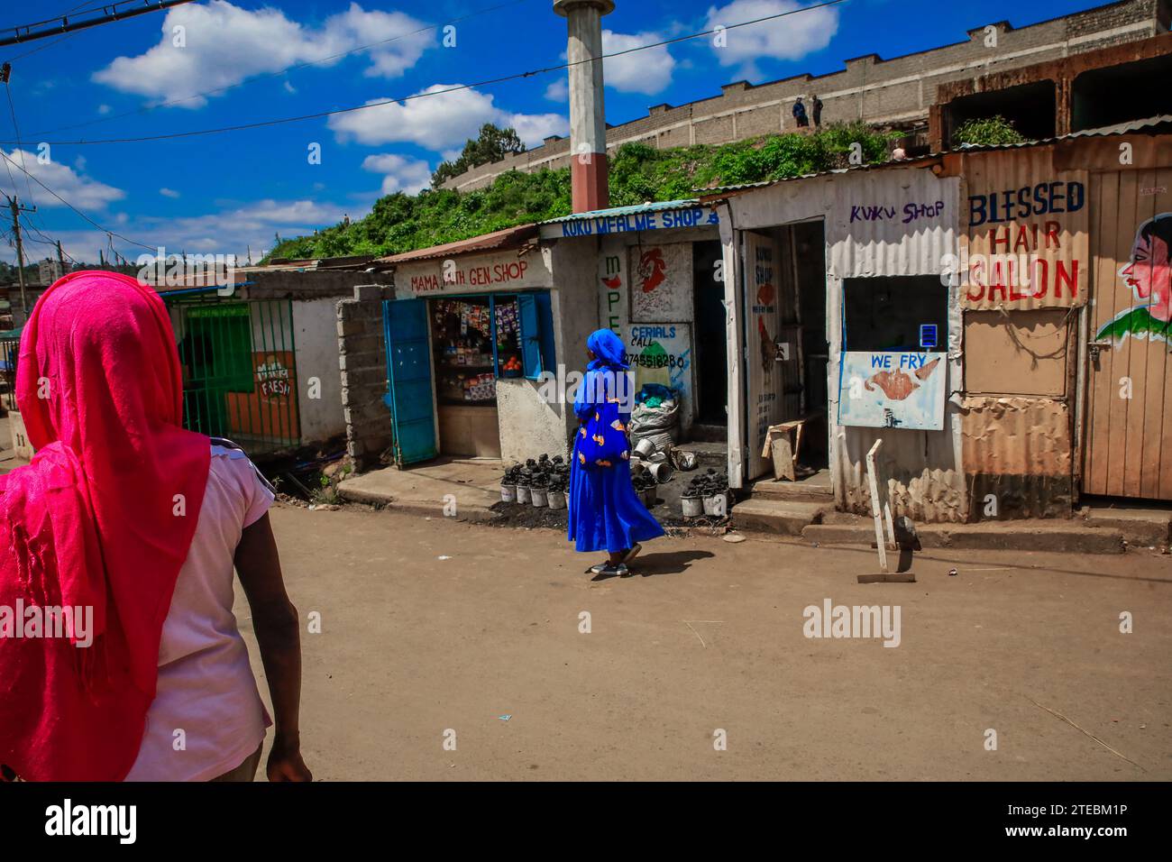 A woman walks past the business streets of Kibera Slum, Nairobi. A view ...
