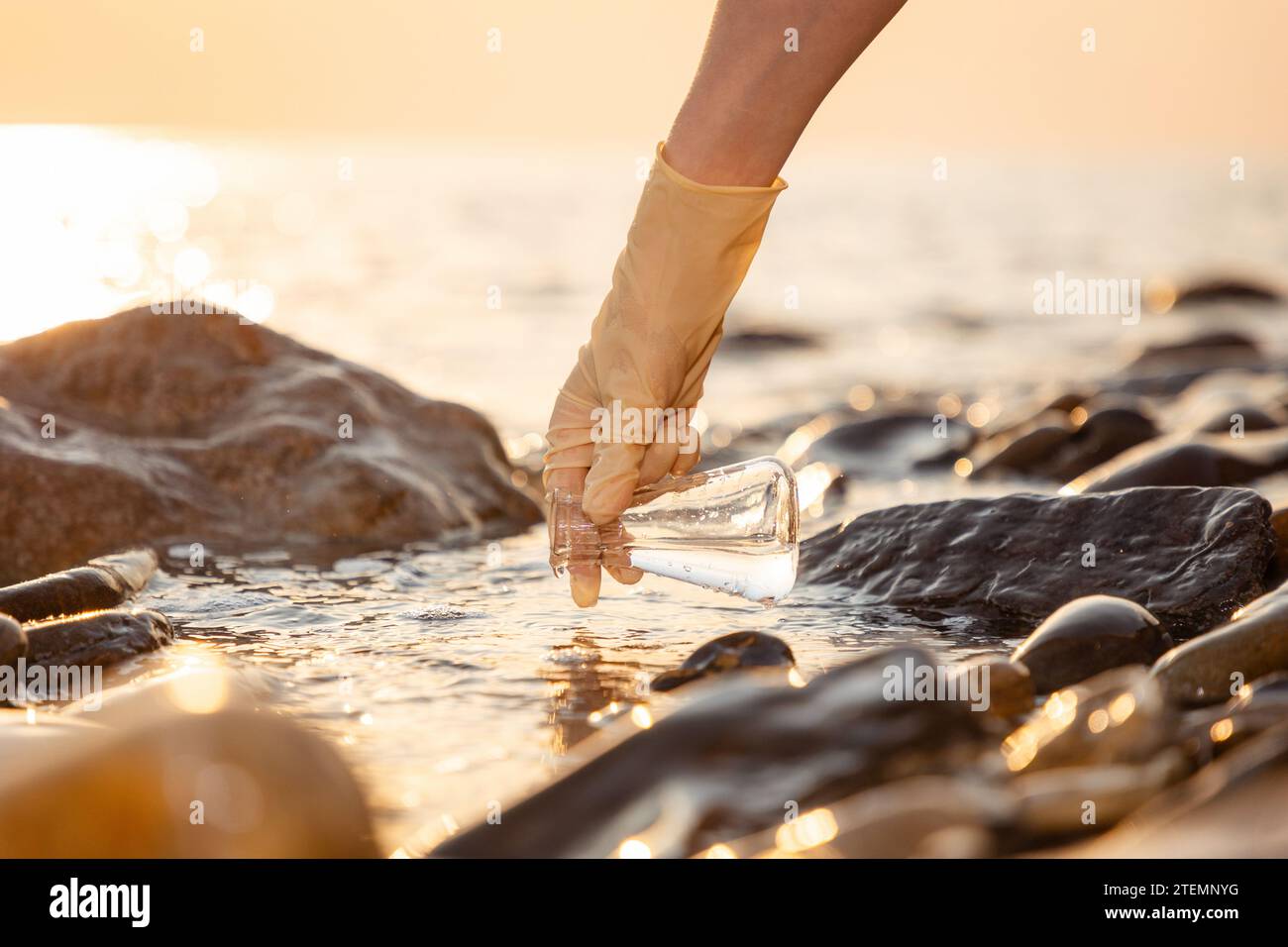 Close up of hand wearing rubber glove intake test sample flask of water ...