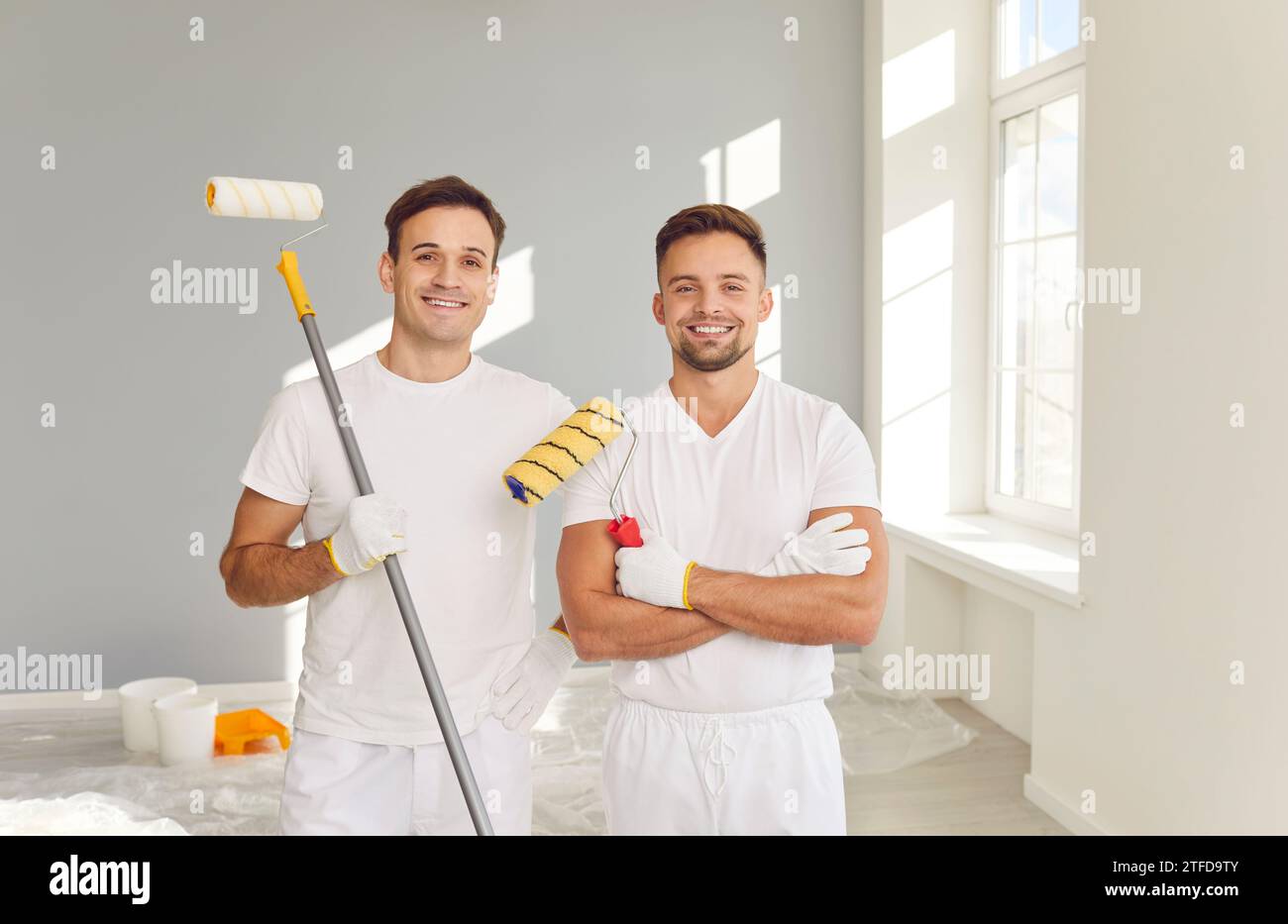 Team of house painters looking at camera holding paint rollers and ...