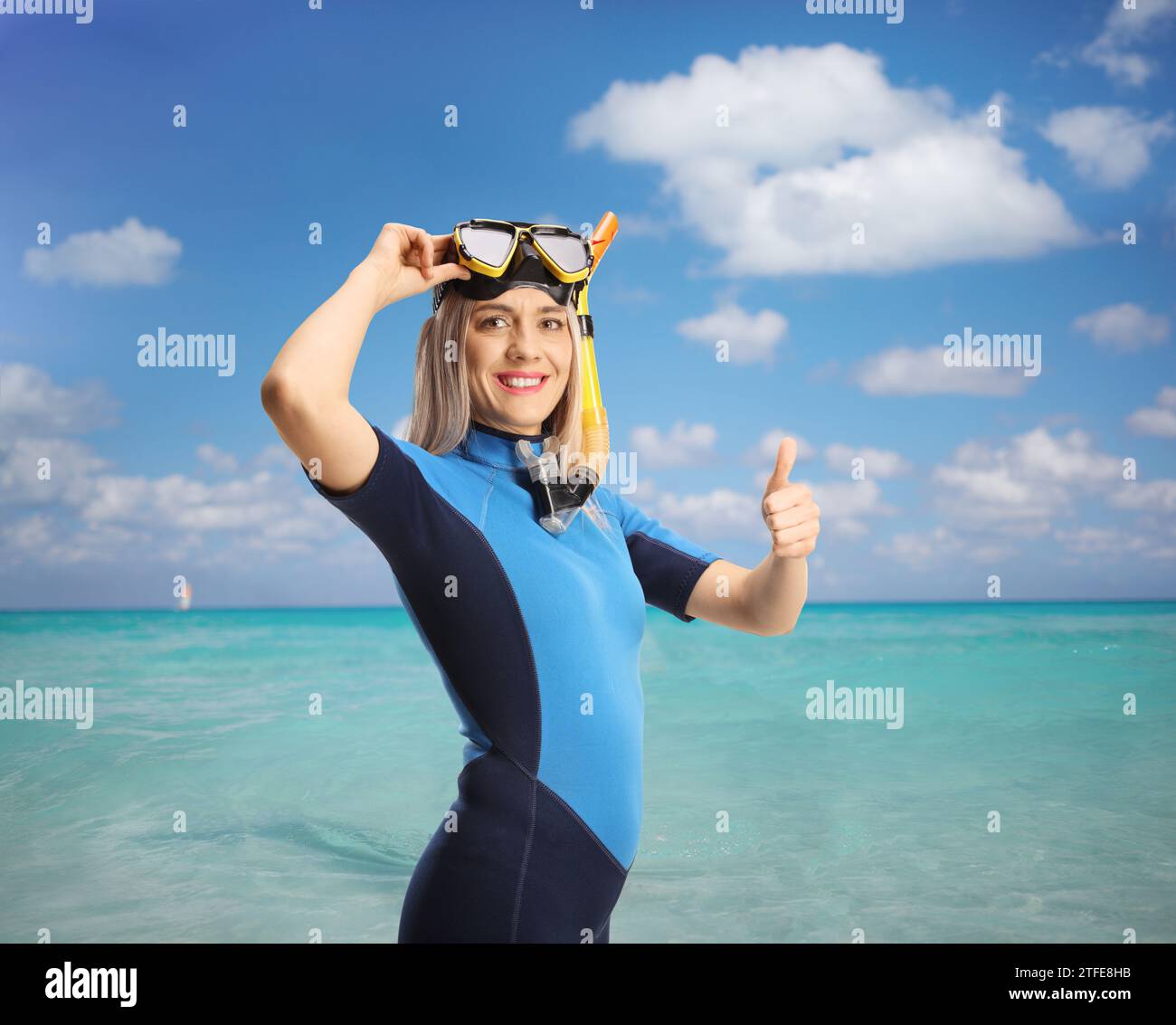 Woman in a wet suit with a dive mask gesturing thumbs up at a sea Stock ...
