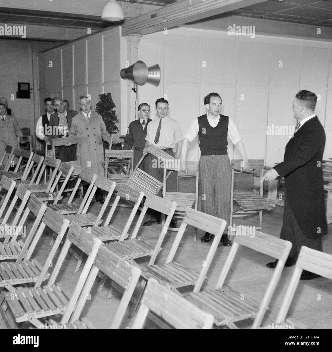 Man in suit gives directions to men who prepare chairs ca. 1950 Stock ...