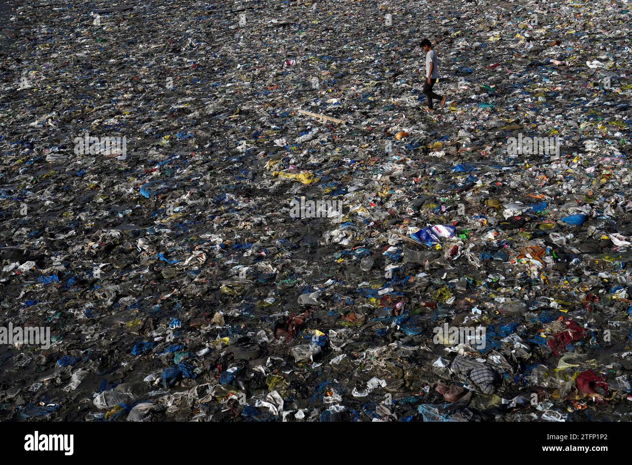 A boy walks on plastic waste at the Badhwar Park beach on the Arabian ...