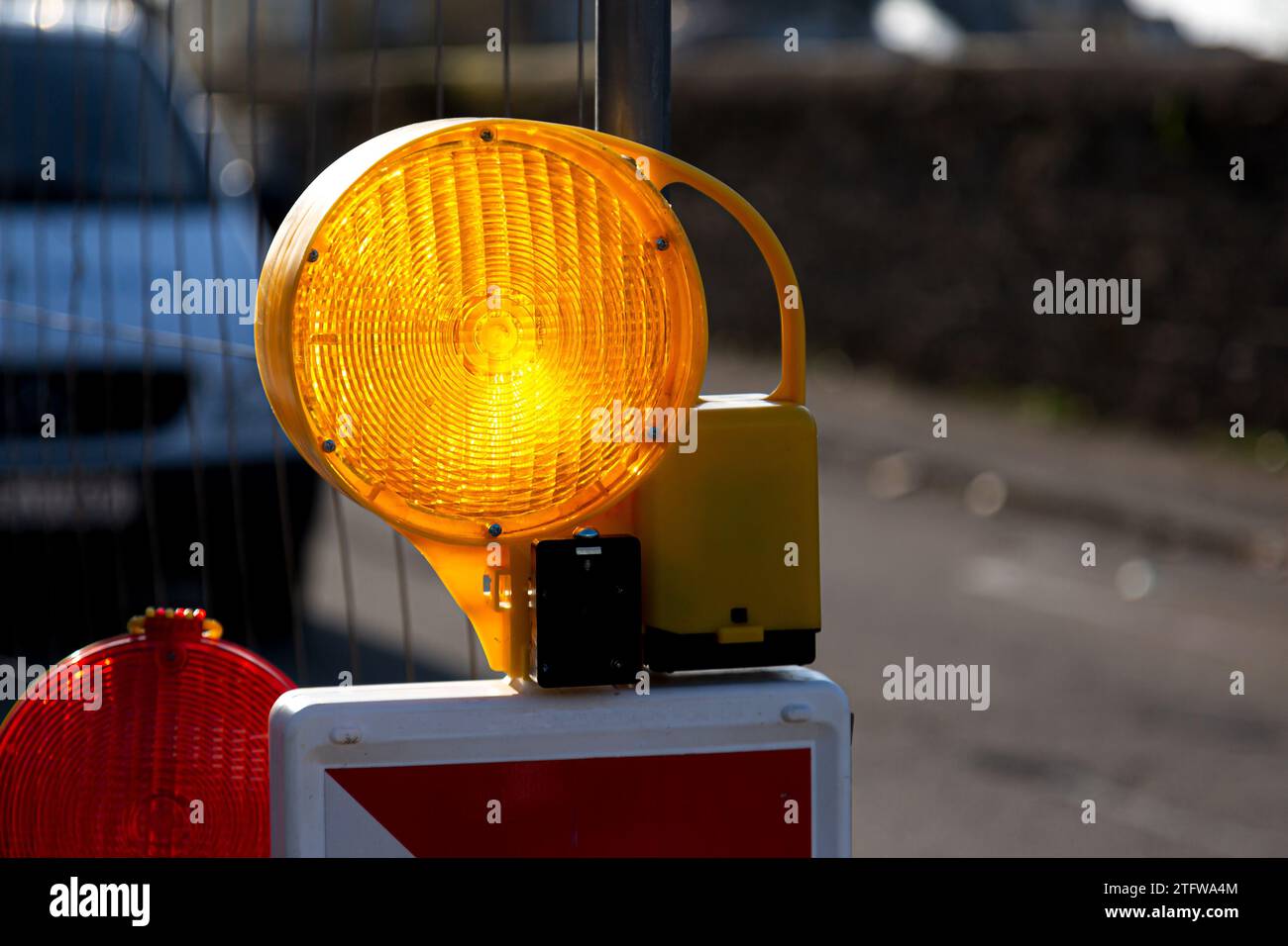 Close-up of yellow and red warning lights with street barriers at a ...