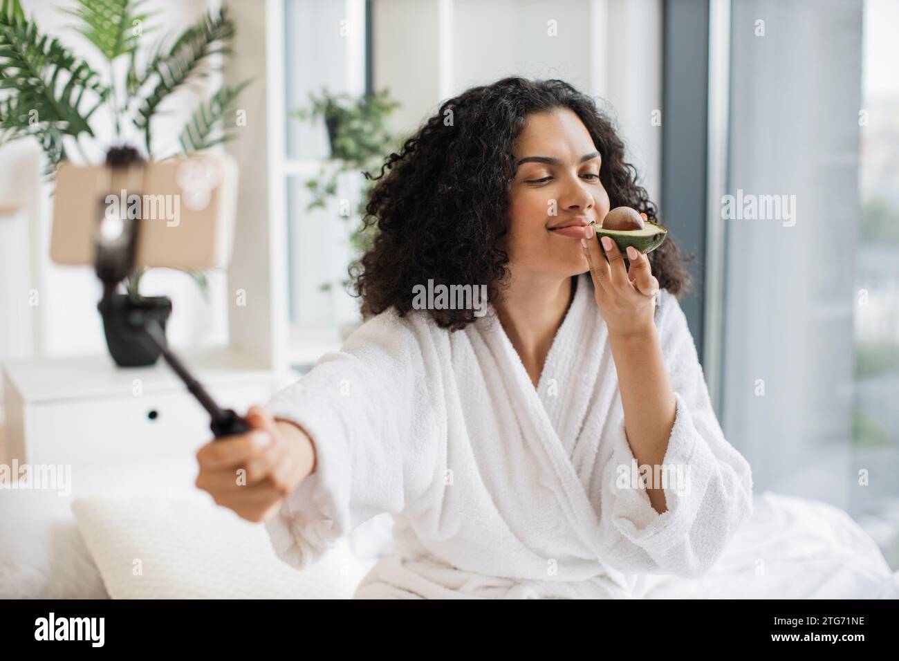 Multiracial female social media influencer enjoying aroma of half of ...