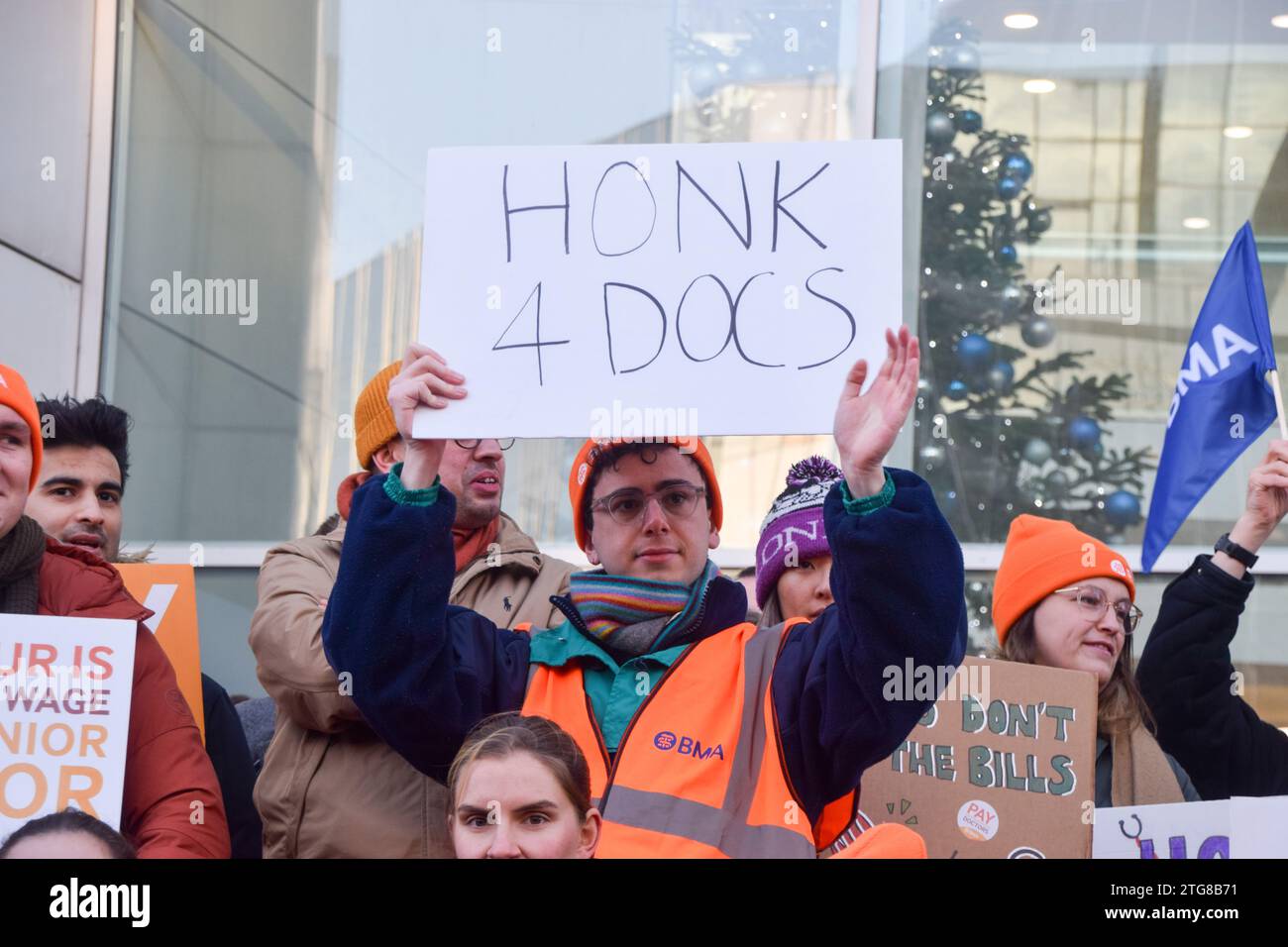 London, UK. 20th Dec, 2023. A junior doctor holds a "Honk for docs ...