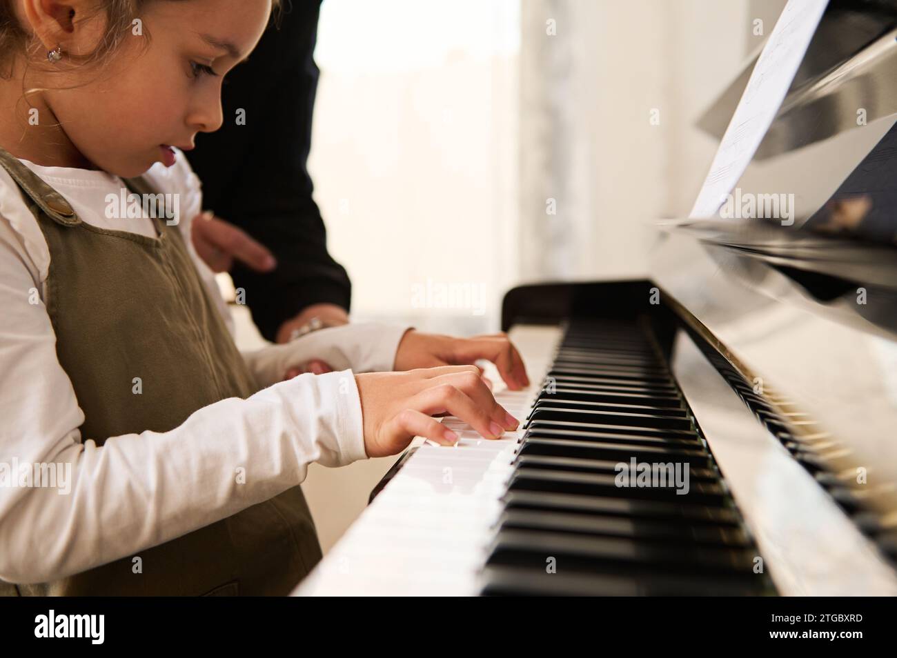 Caucasian little child girl playing grand piano, touching piano keys ...