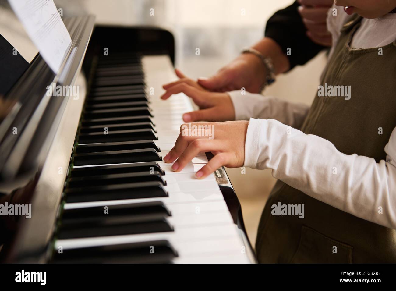 Side view of child's hands on piano keyboard, touching white and black ...