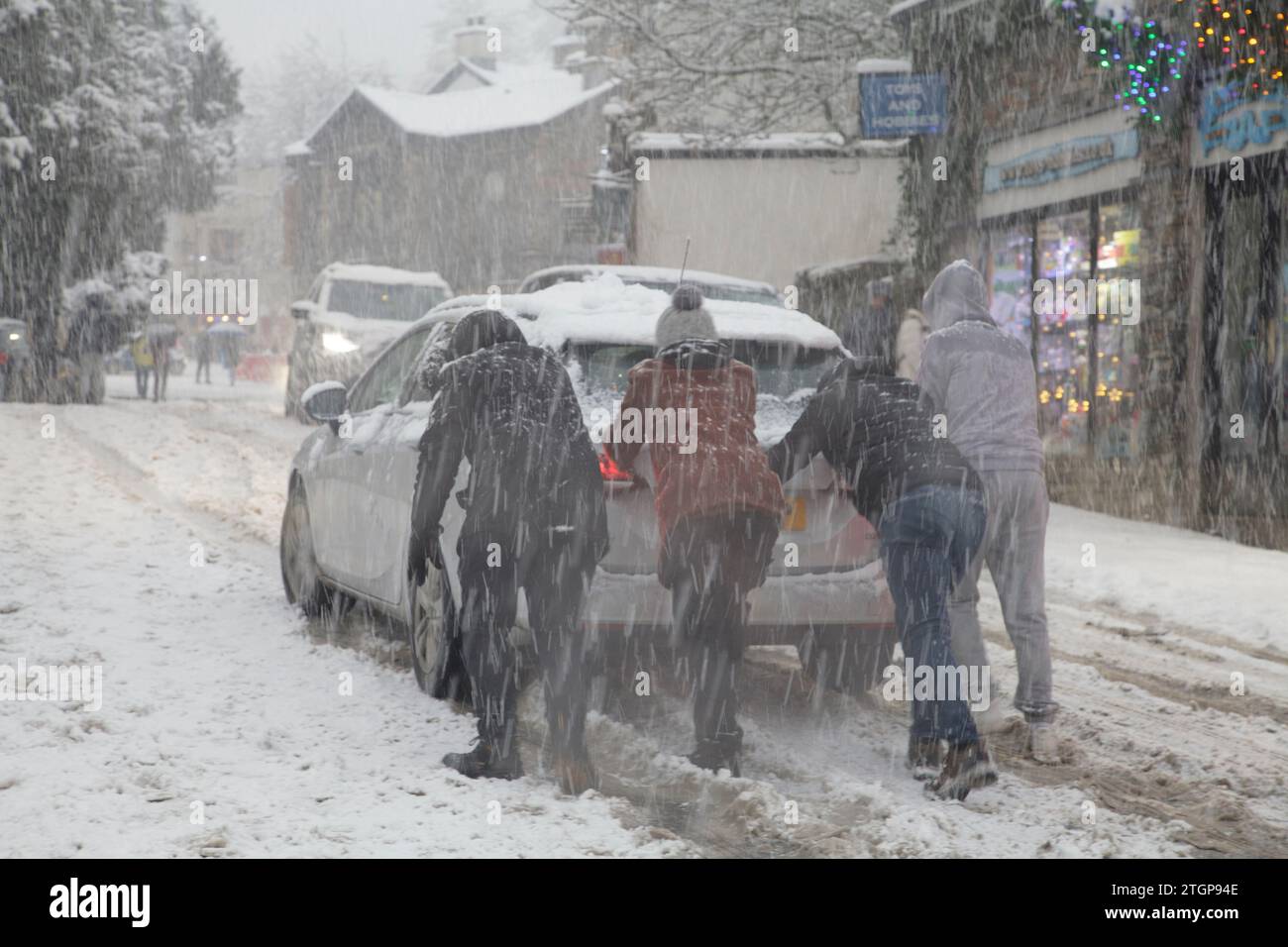Members of the public push a stranded car up an incline during a ...