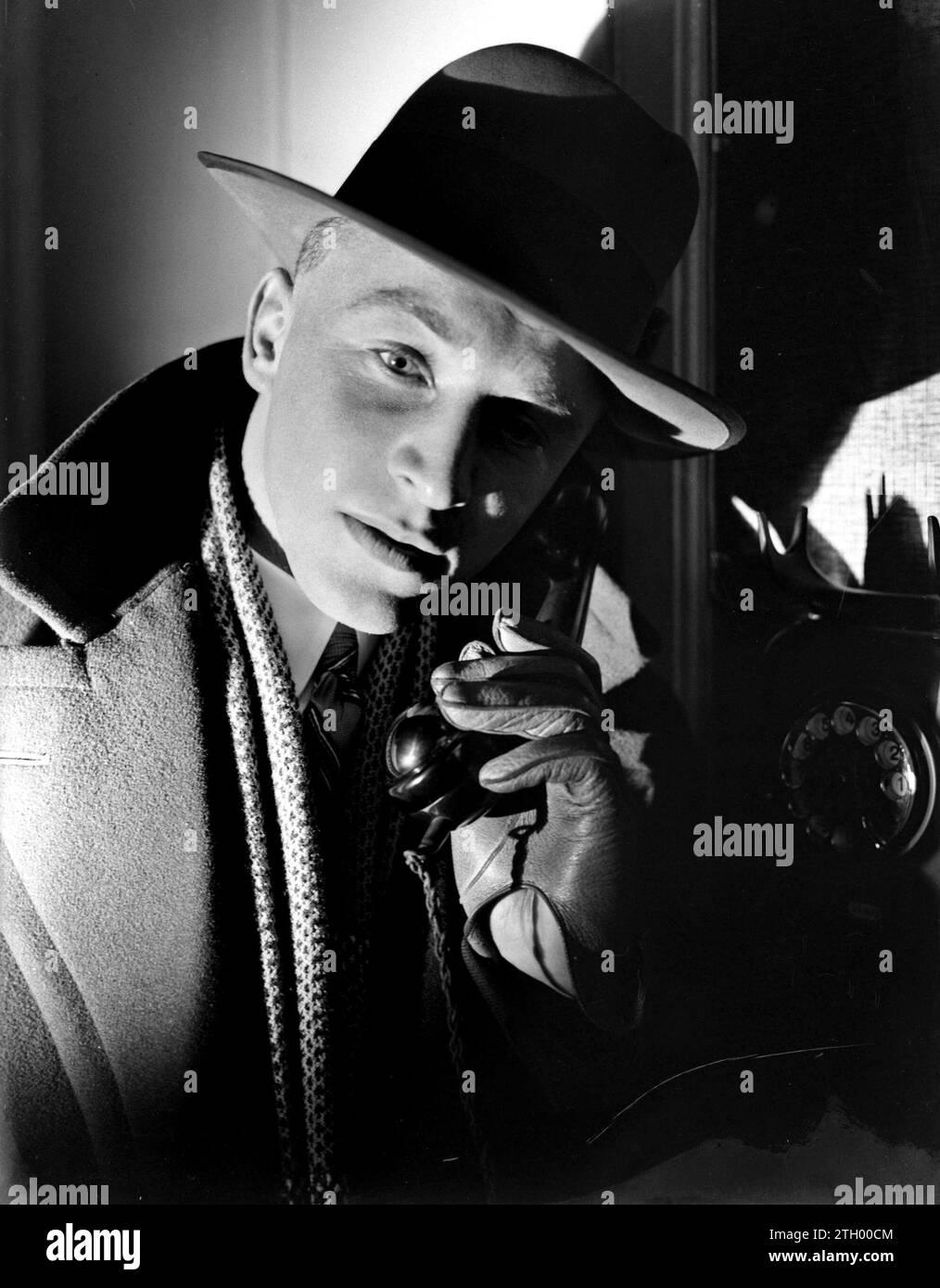 Man wearing a hat with telephone receiver in gloved hand, right ...