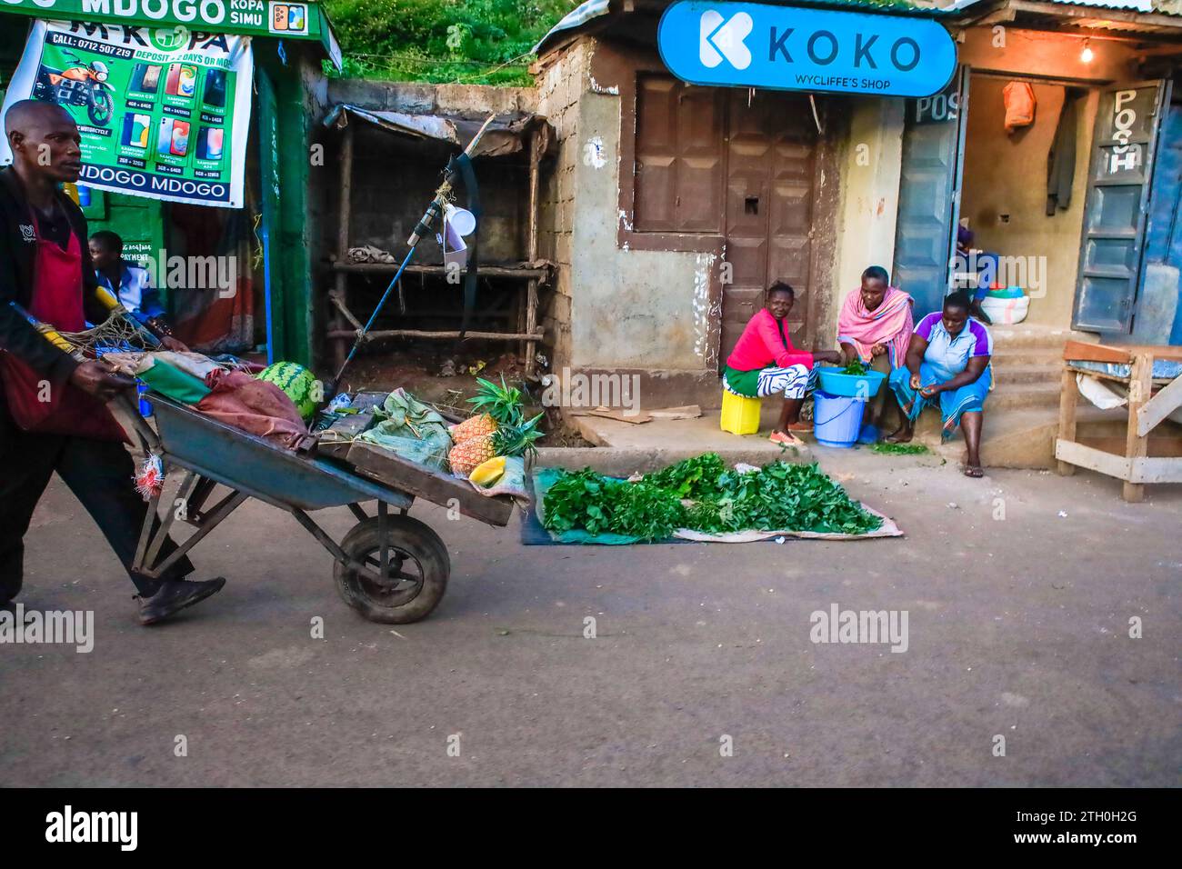 A man walks past the streets selling fruits on his wheelbarrow in ...