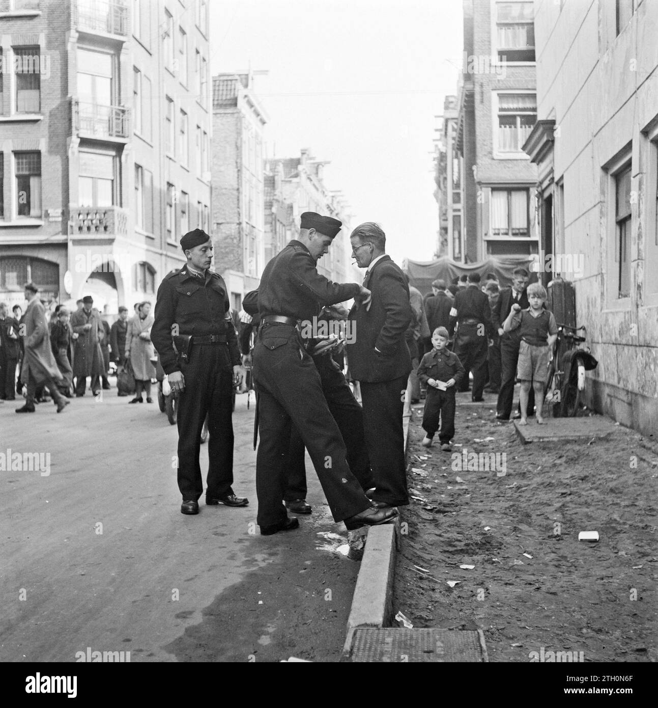 Police conducting a black market raid, searching suspects ca. October ...