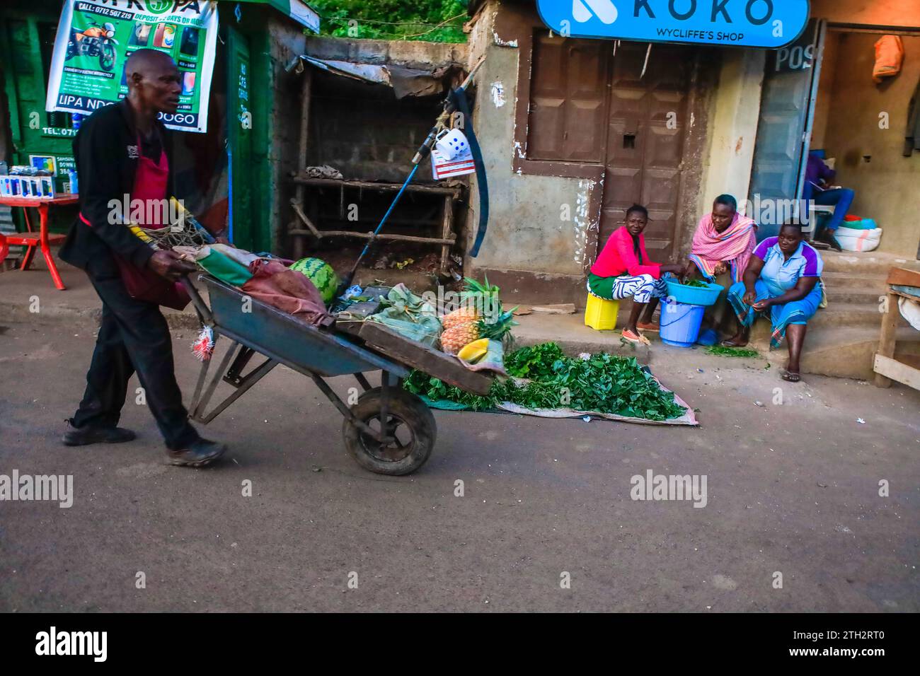 A man walks past the streets selling fruits on his wheelbarrow in ...