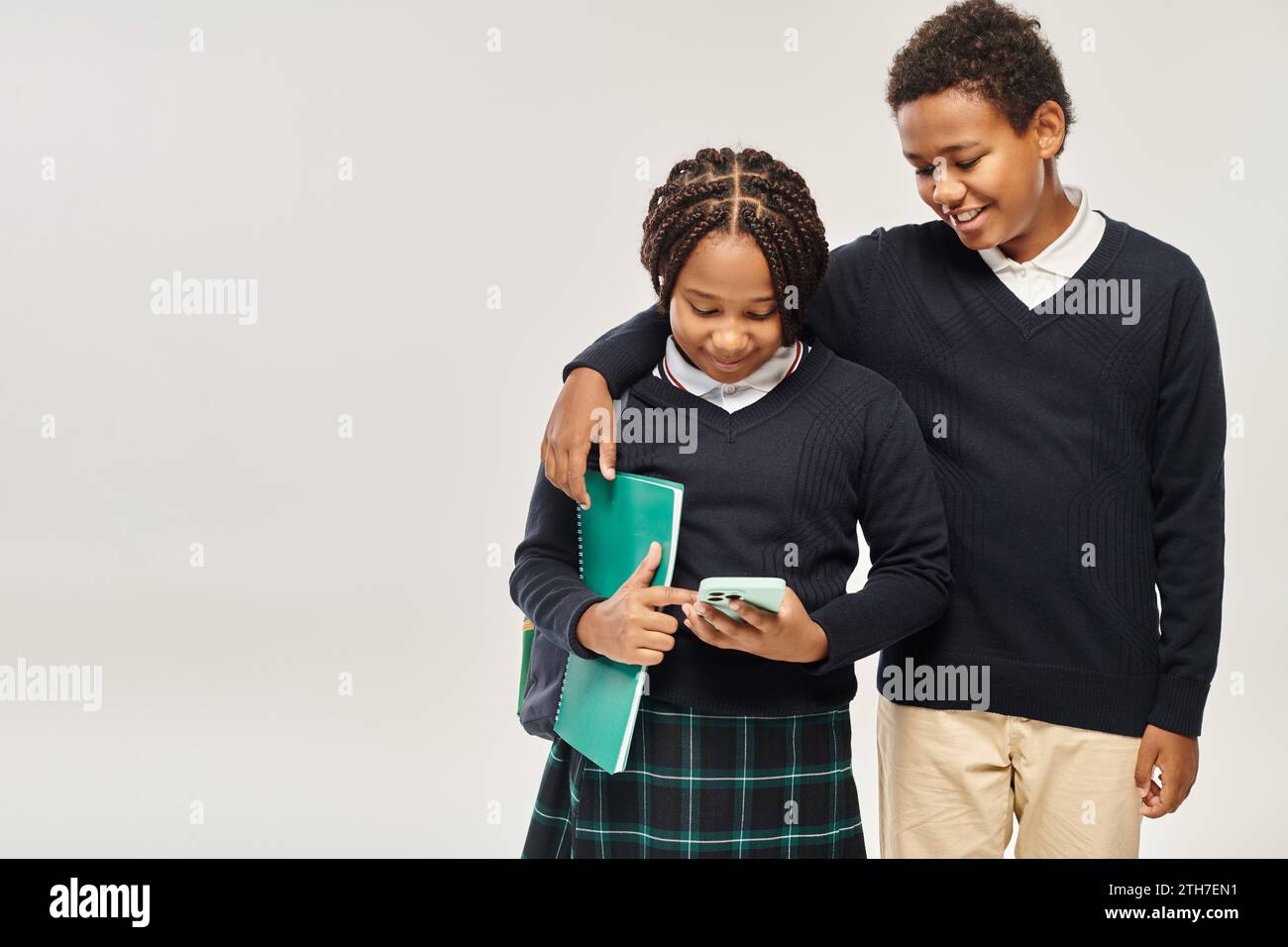 happy african american schoolboy hugging girl in uniform with ...
