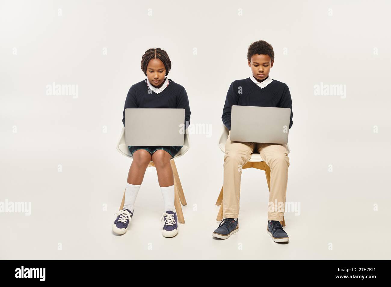 concentrated african american schoolkids in uniform using laptops and ...