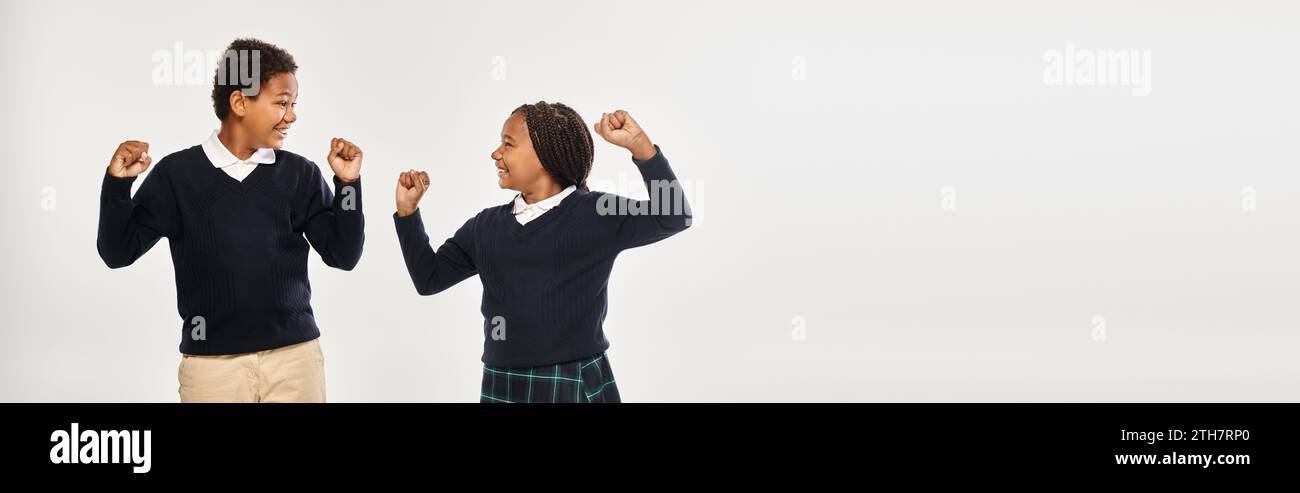 excited african american schoolkids in uniform rejoicing while standing ...