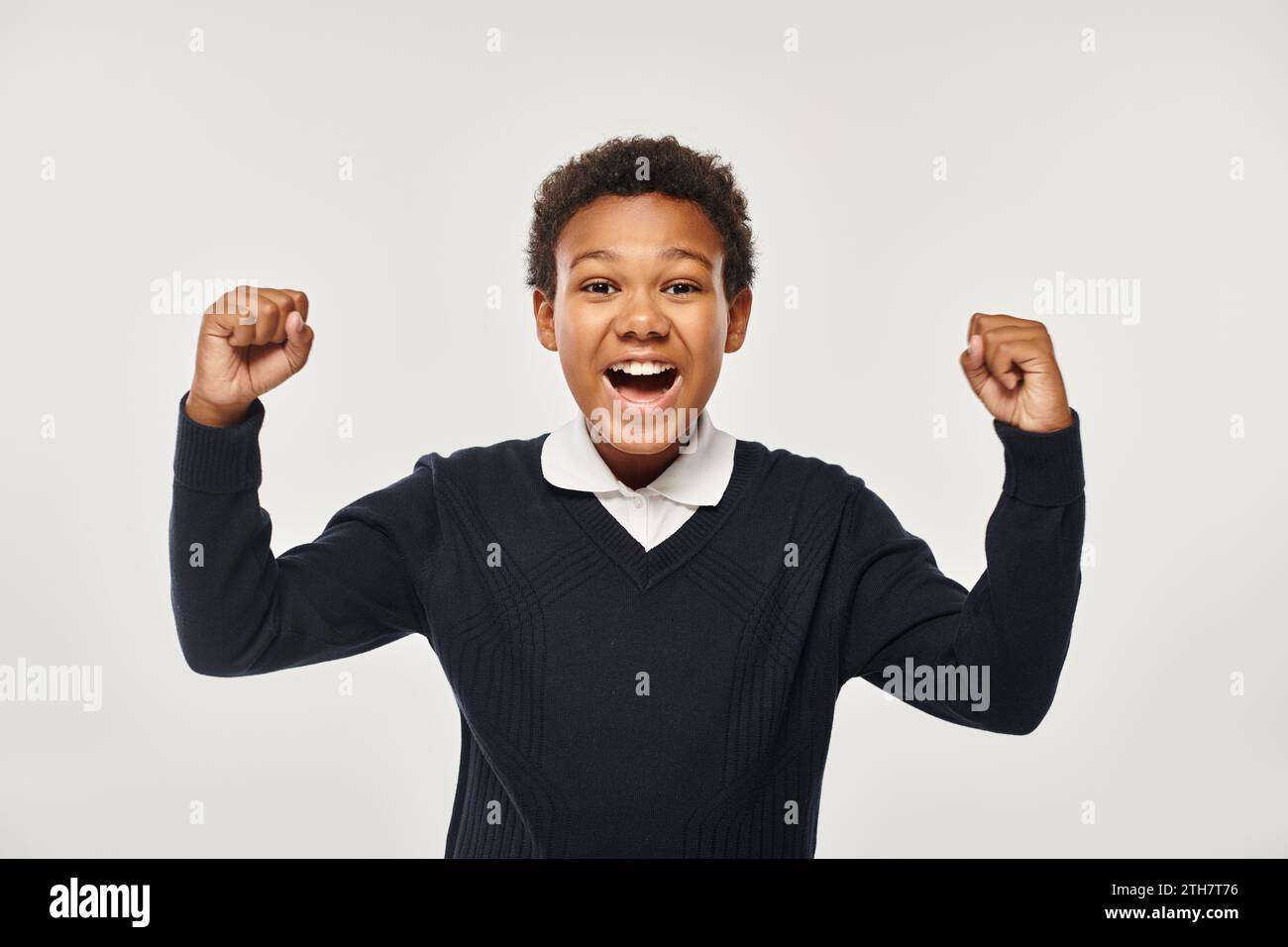 excited african american schoolboy in uniform rejoicing while looking ...