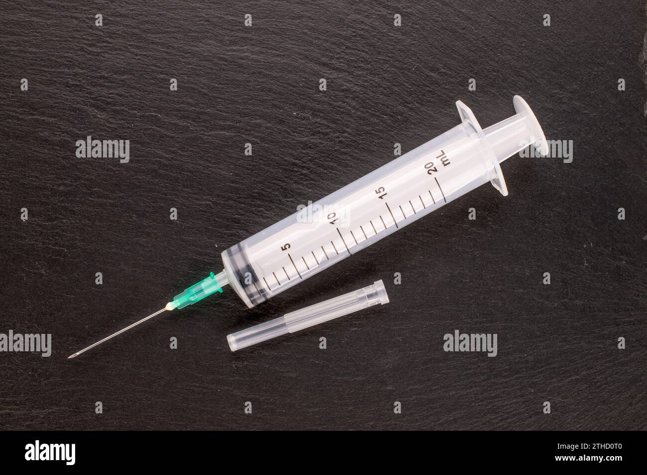 One plastic medical syringe with needle on slate stone, macro, top view ...