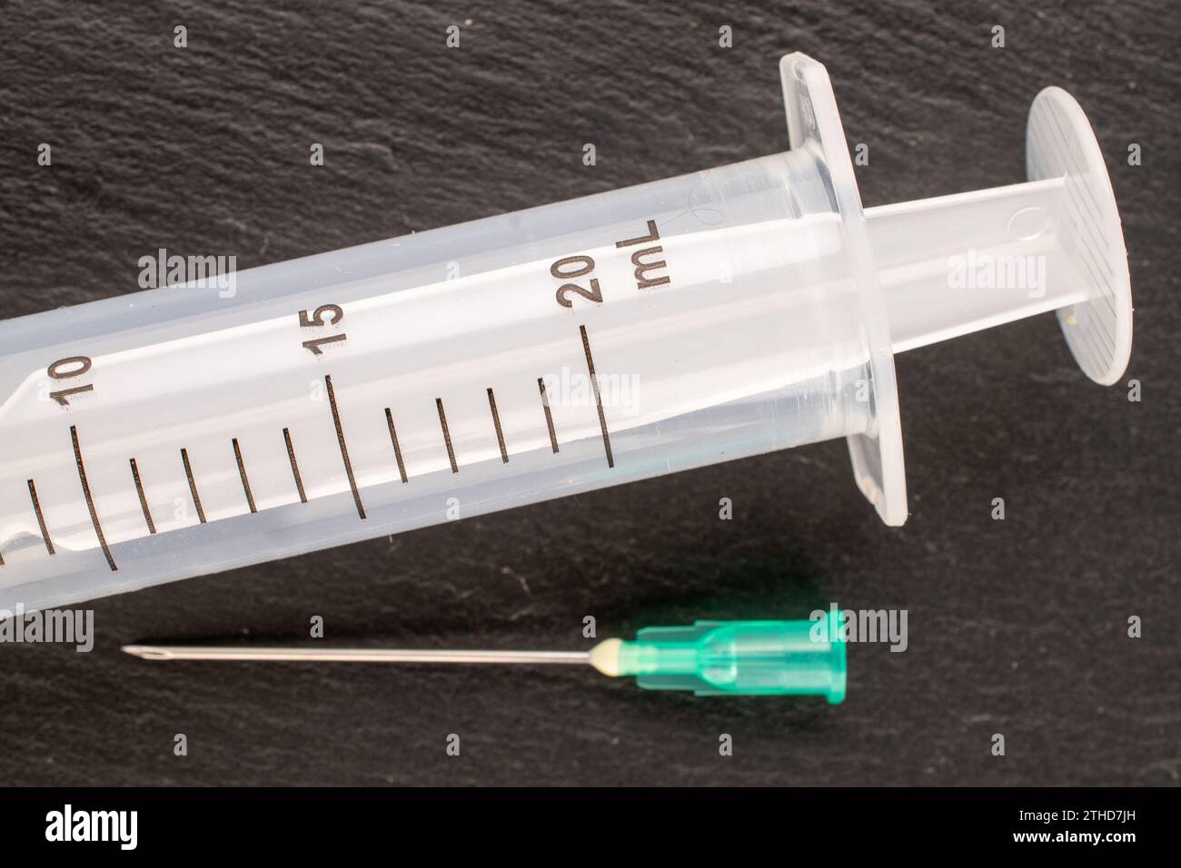 One plastic medical syringe with needle on slate stone, macro, top view ...