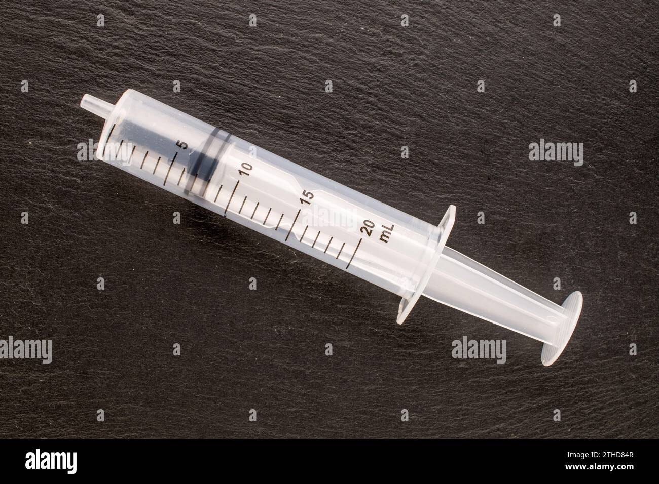 One plastic medical syringe on slate stone, macro, top view Stock Photo ...