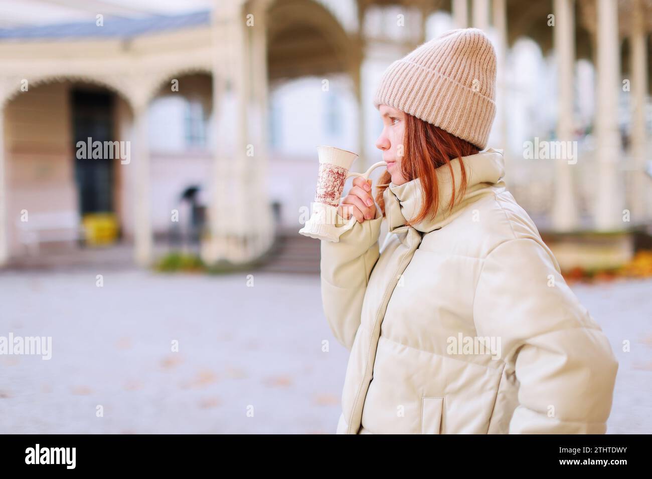 Young girl drinking from cup with therapeutic mineral water at a ...
