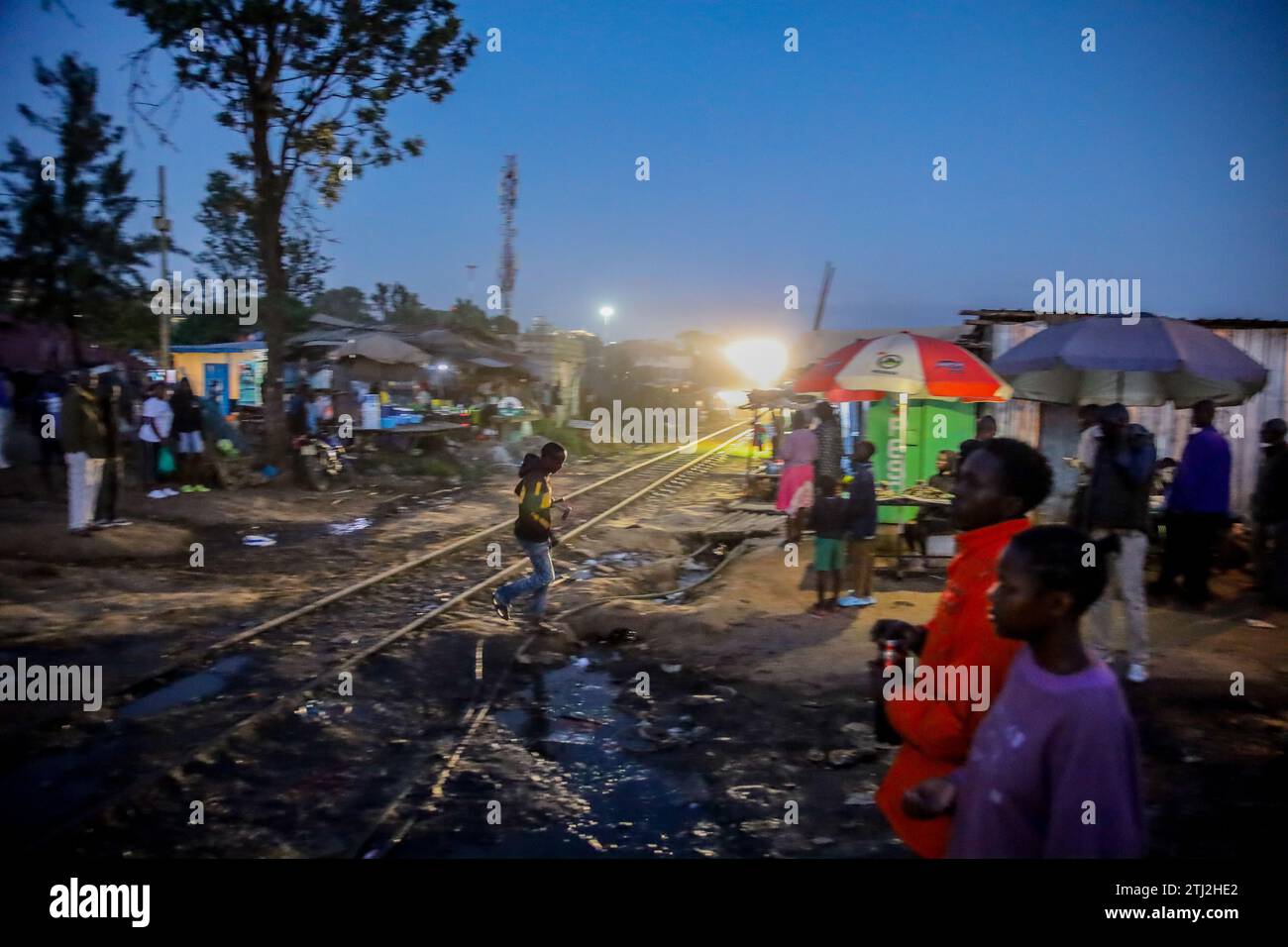 Residents walk past a train line running through the center of Kibera ...