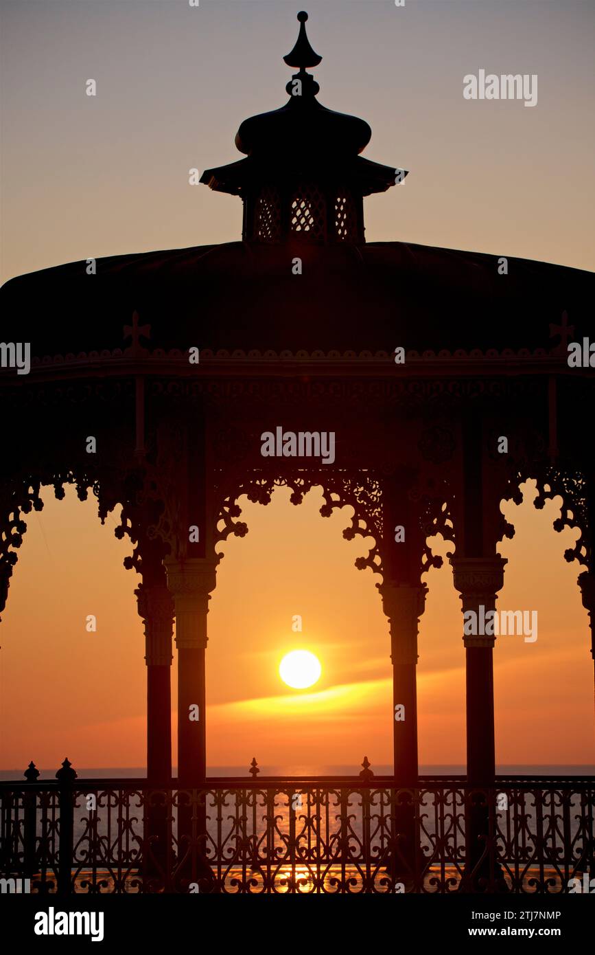 Silhouetted shape of Brighton's Victorian Bandstand with setting sun ...
