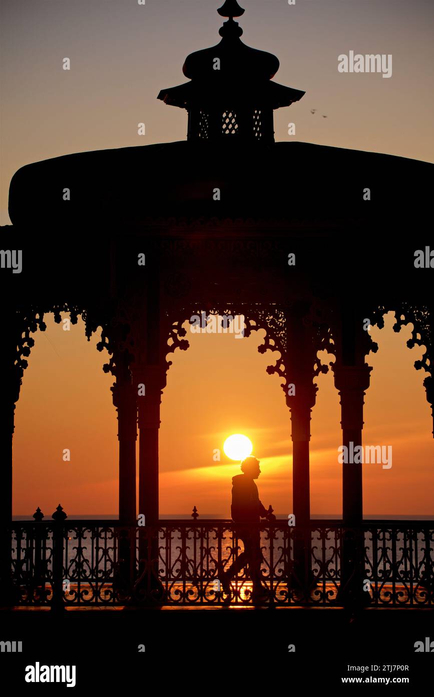 Silhouetted shape of Brighton's Victorian Bandstand with a solitary man ...