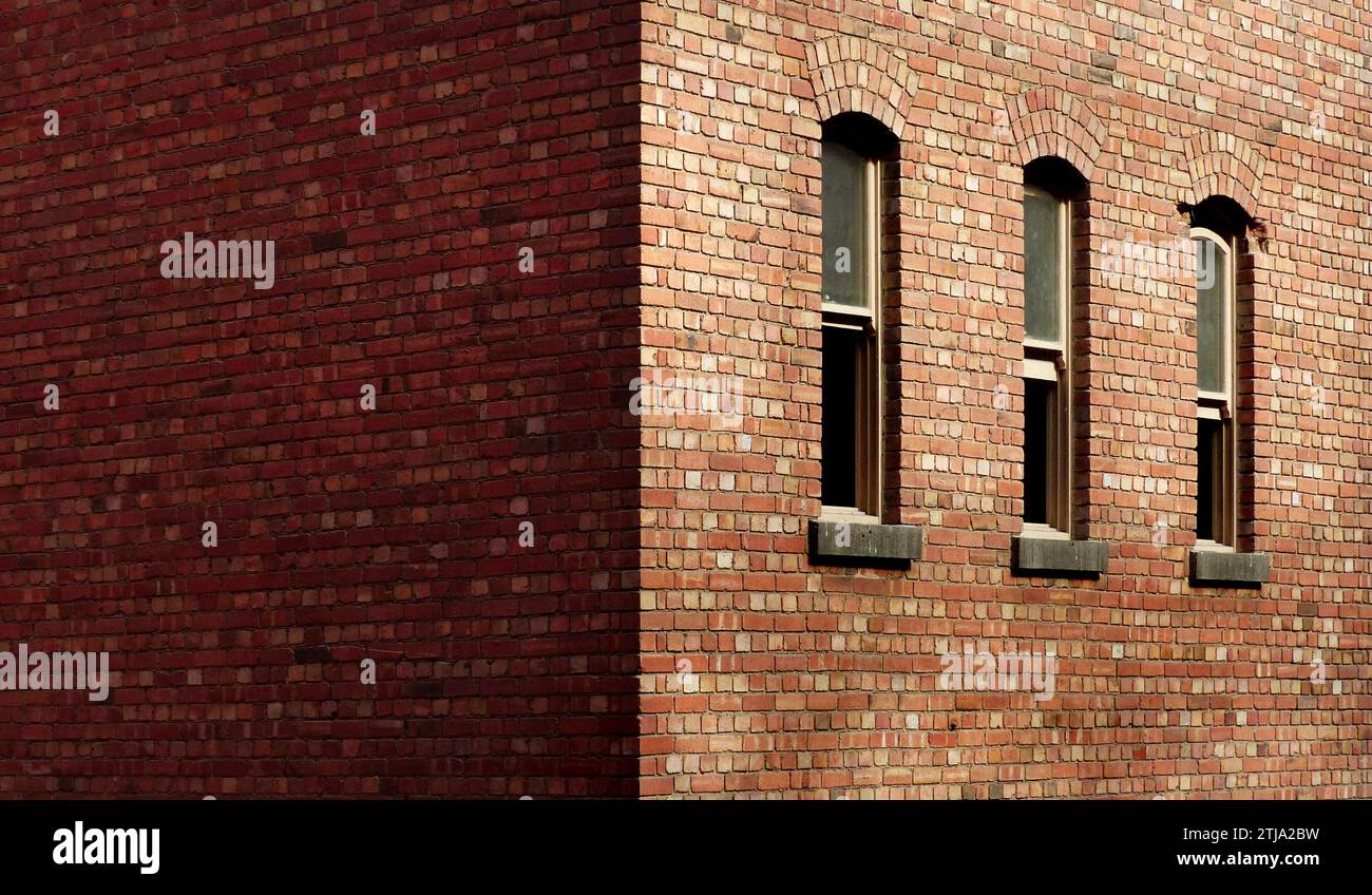 A brick building with three windows on the sunlit aspect. Fired bricks ...