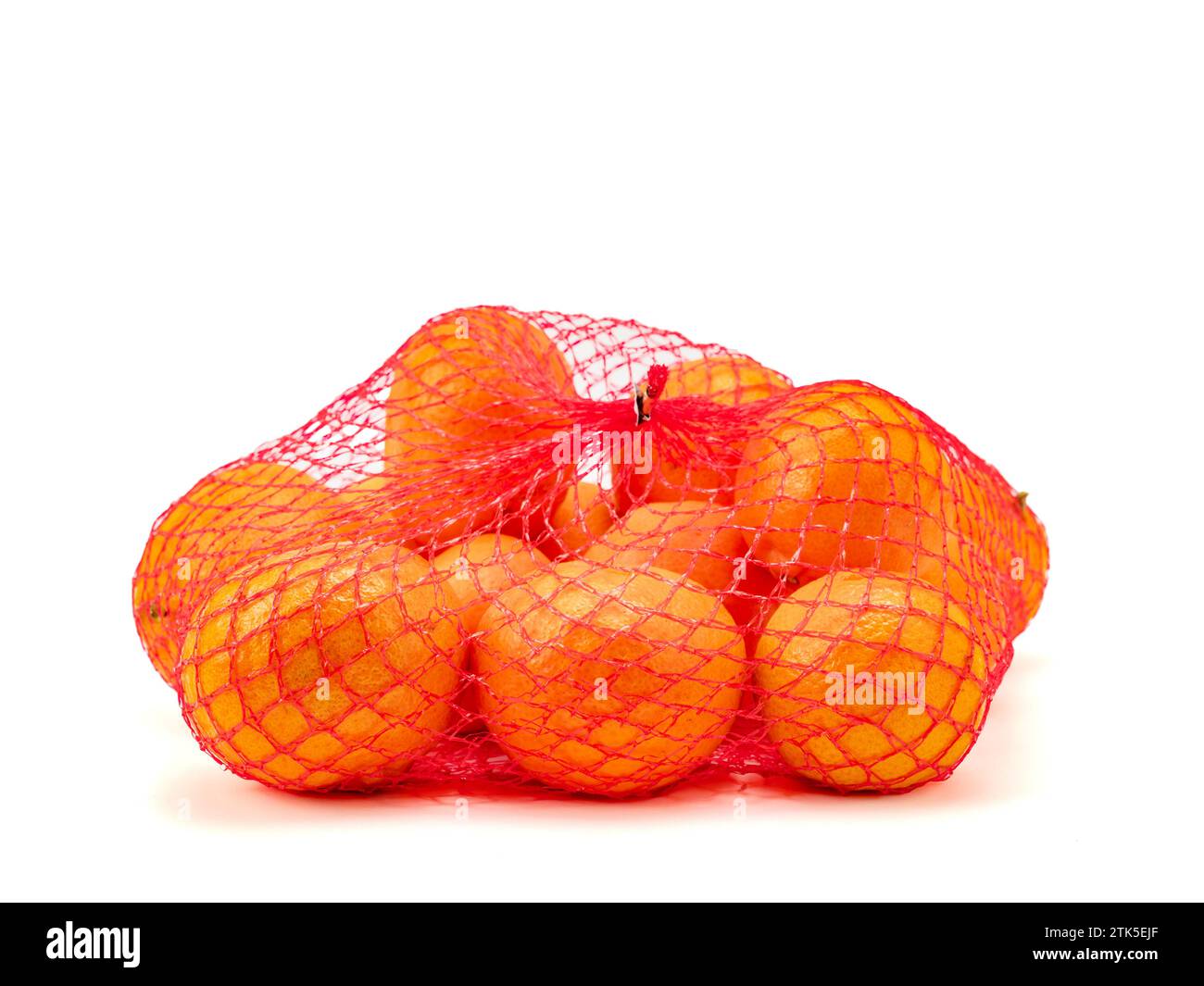 A group of tropical tangerine fruits in a mesh package on a white ...