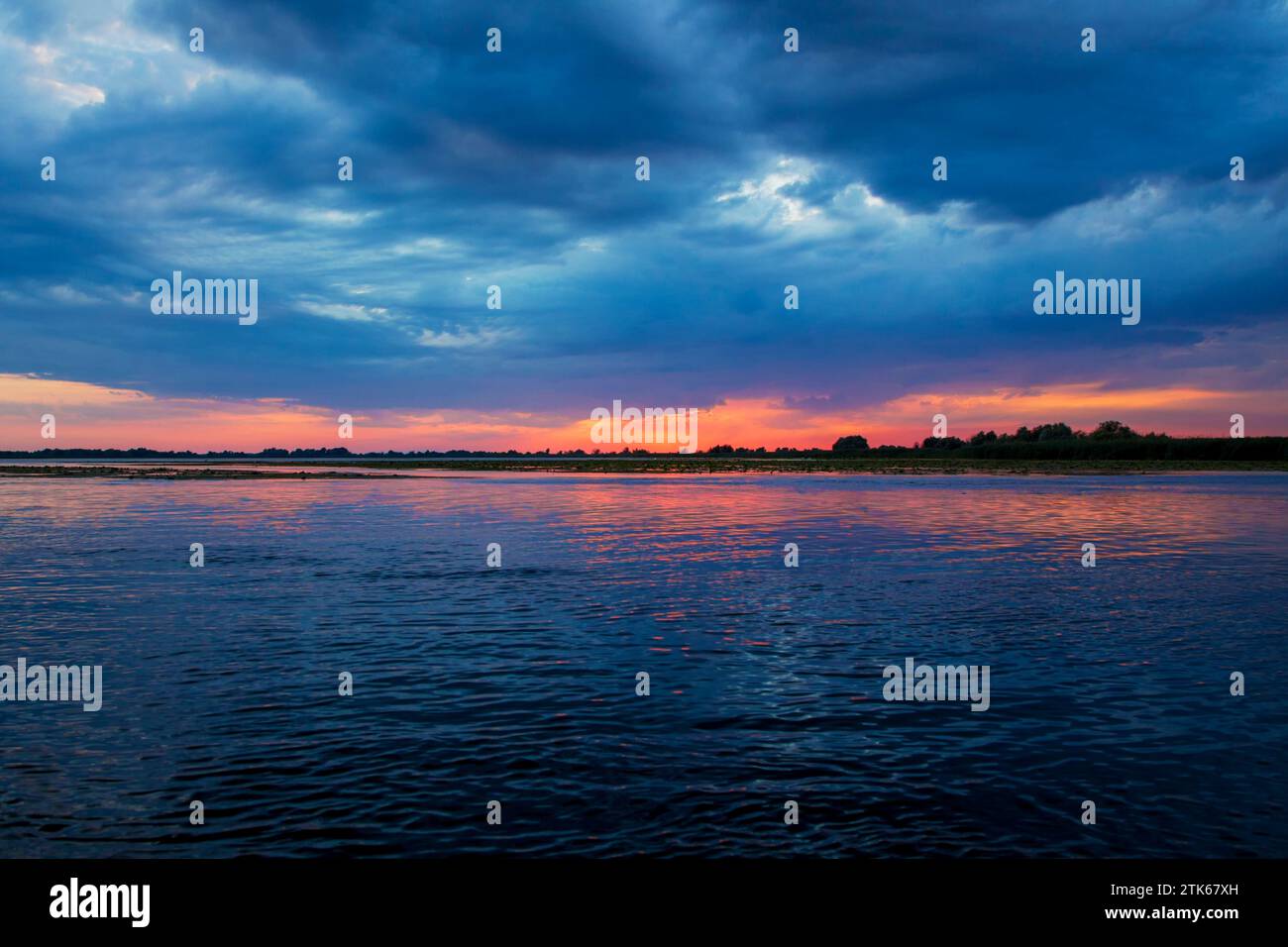 Colourful sky as sunset approaches over one of the Danube Delta lagoons ...