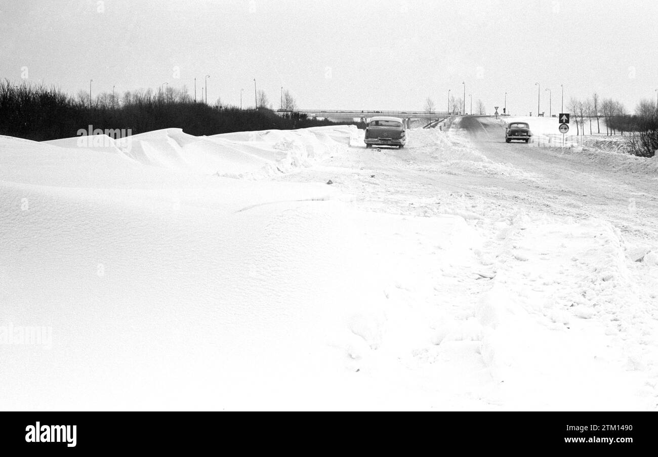 Cars driving through deep snow on a highway in the Netherlands ca. 1963 ...