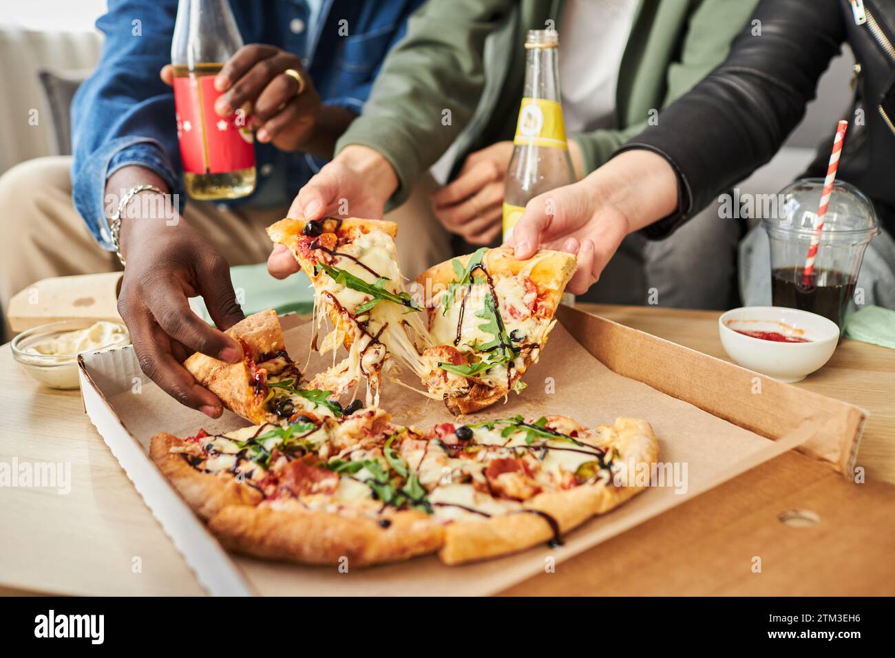 Friends Sharing Delicious Pizza with Stretched Cheese Stock Photo - Alamy