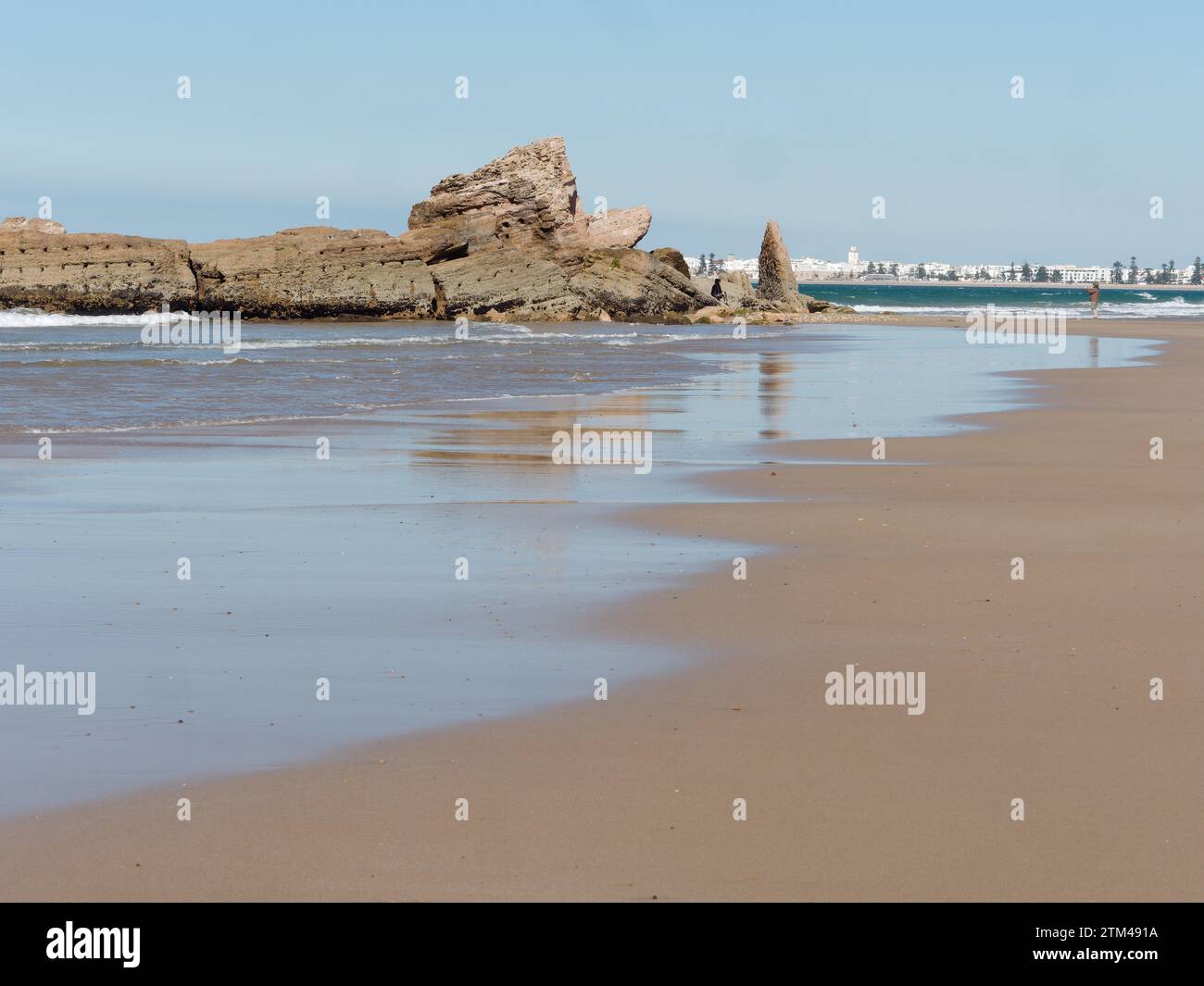 Rock outcrop on a sandy beach with the medina in the distance in the ...