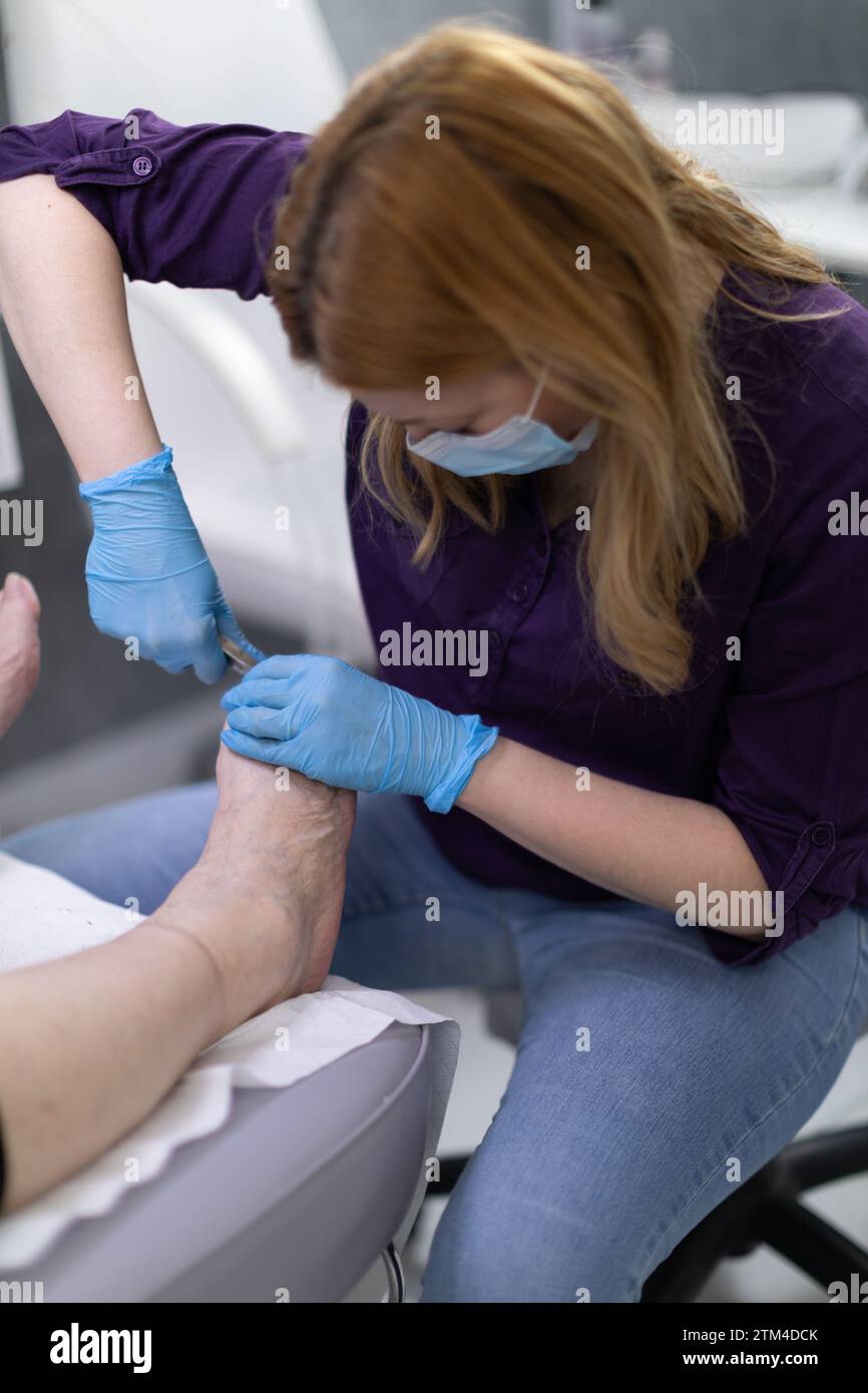 The podiatrist carefully performs a therapeutic pedicure for his client ...