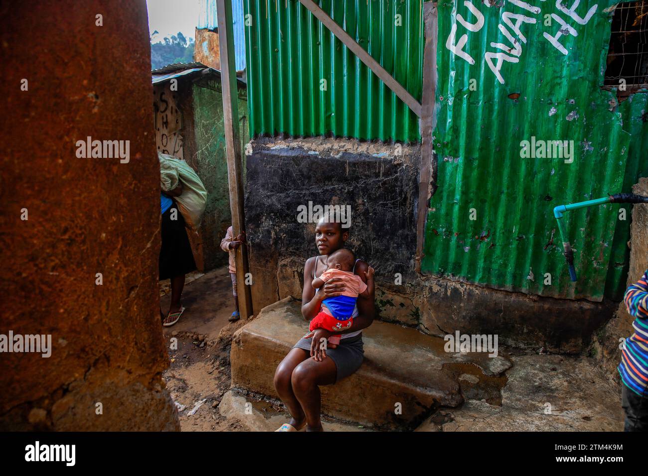 A woman and her child are seaated outside the neighborhoods in Kibera ...