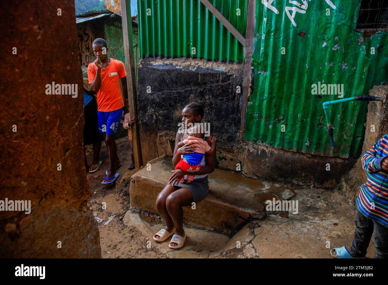 A woman and her child are seaated outside the neighborhoods in Kibera ...