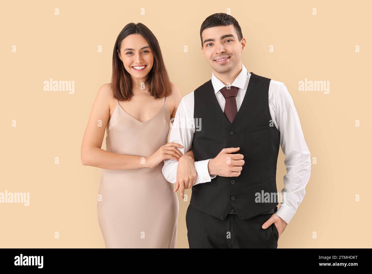 Elegant young couple on beige background Stock Photo - Alamy