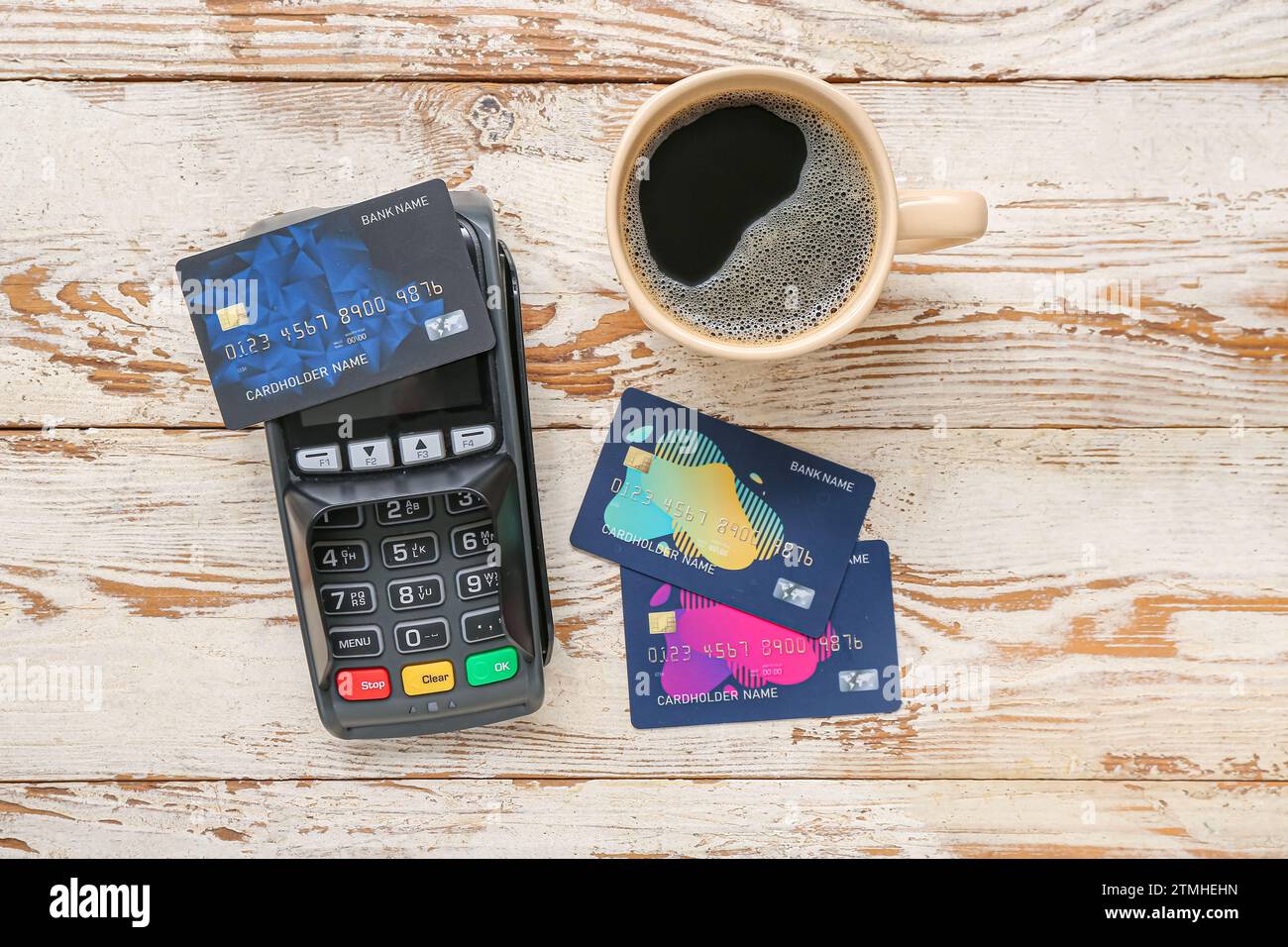 Payment terminal with credit cards and coffee cup on white wooden ...