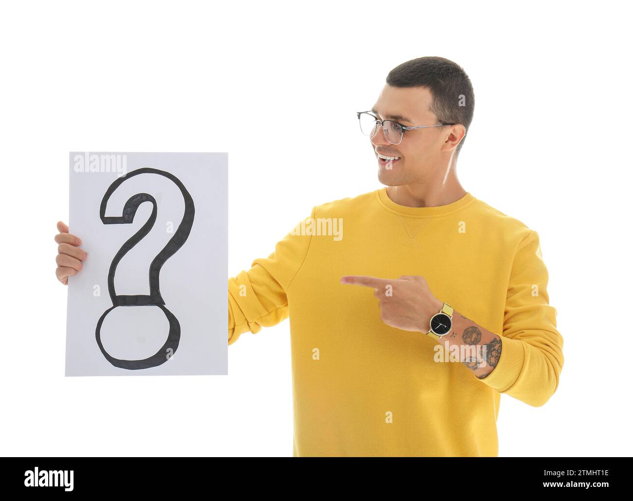 Young man pointing at paper with question mark on white background ...