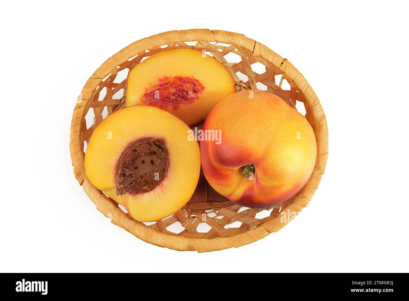 Ripe nectarine fruit with half in a wicker basket isolated on white ...