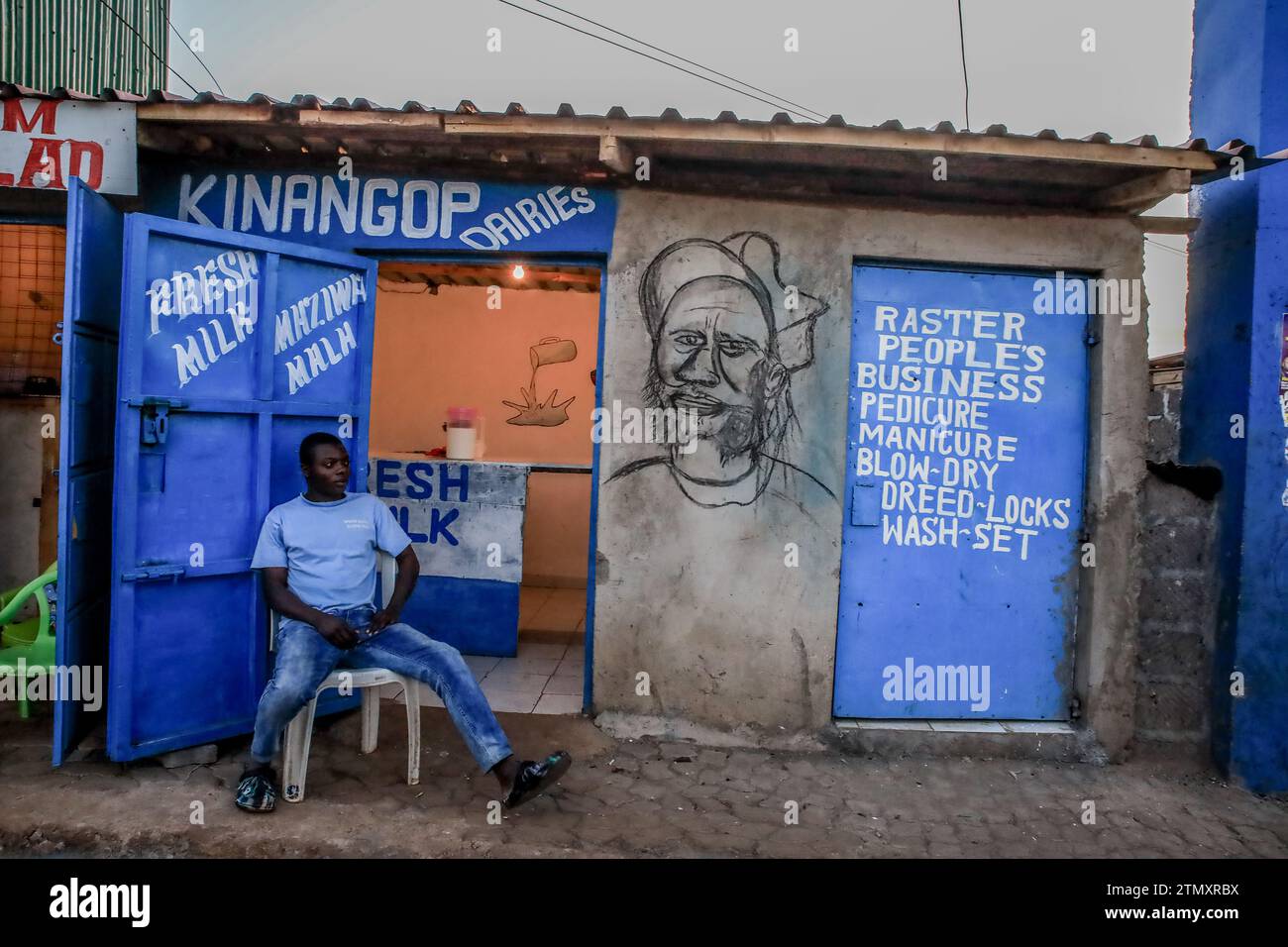 A man is seated outside his shop in Kibera Slum, Nairobi. A view ...
