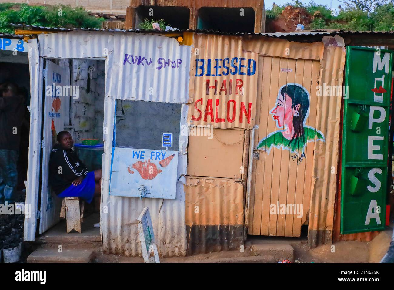 A woman is seated inside her shop in Kibera Slum, Nairobi. A view ...