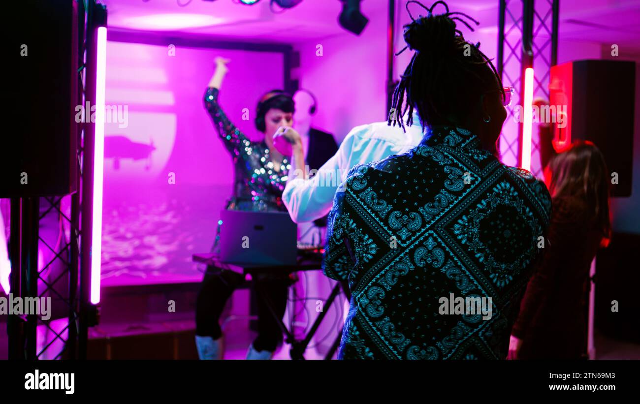 Young adult putting music at party, working as DJ at discotheque with ...