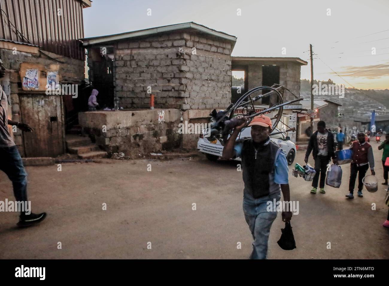 A cutler walks past the streets in Kibera Slum carrying his tool of ...