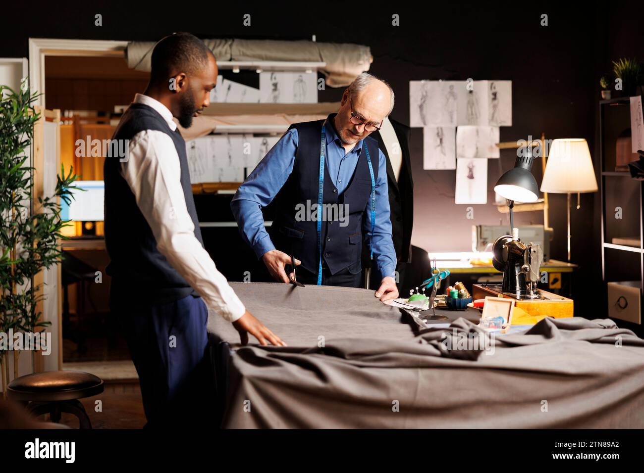Meticulous elderly master tailor cutting fabric sheet for upcoming ...