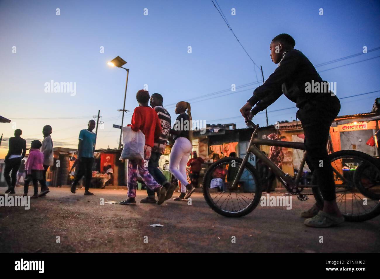 Residents walk past the busy business streets in Kibera Slum, Nairobi ...